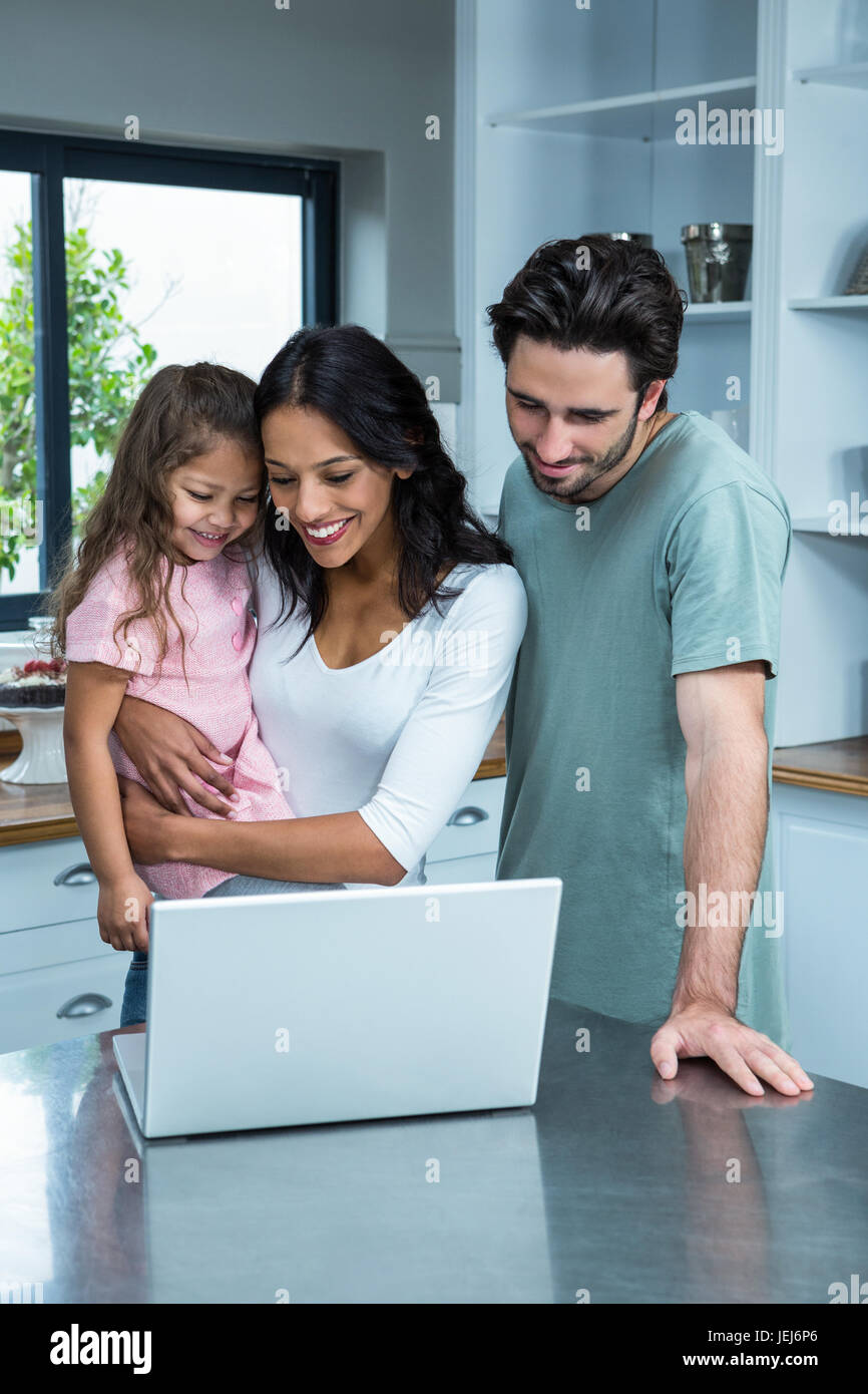 Smiling parents using laptop with daughter Stock Photo - Alamy