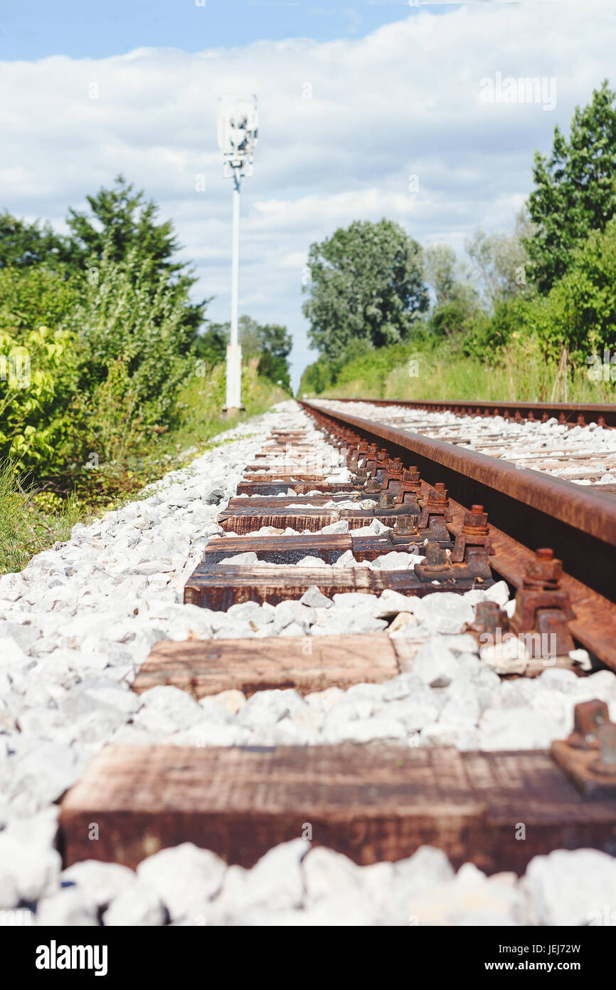 Rusted railroad tracks and sleepers on white gravel, surrounded with ...