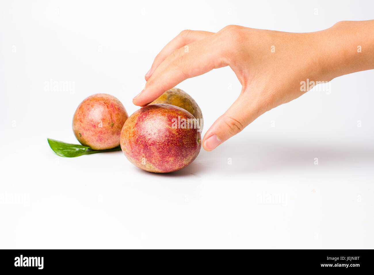 Female hand reaching passion fruit on white Stock Photo - Alamy