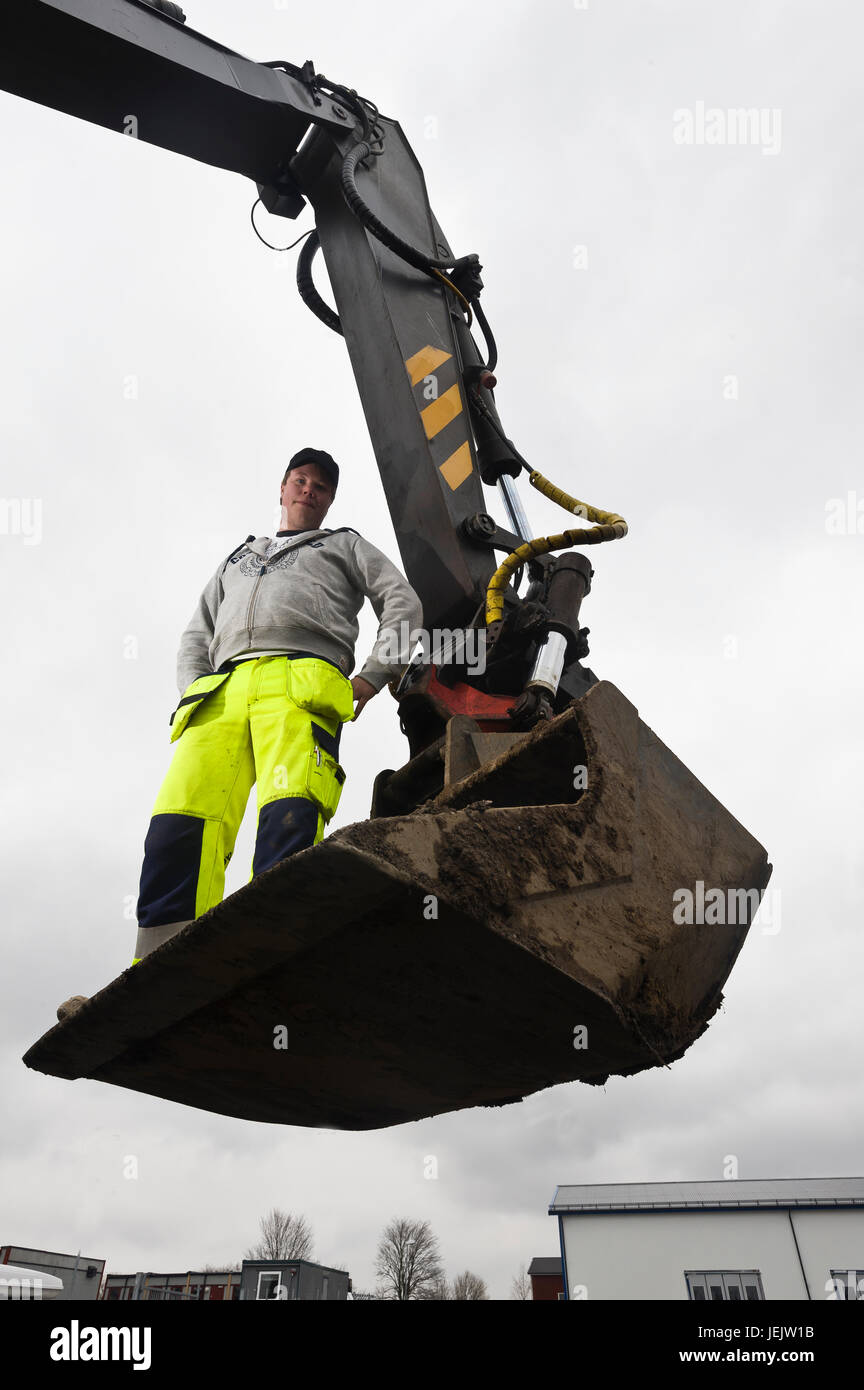 Worker standing on scoop Stock Photo - Alamy