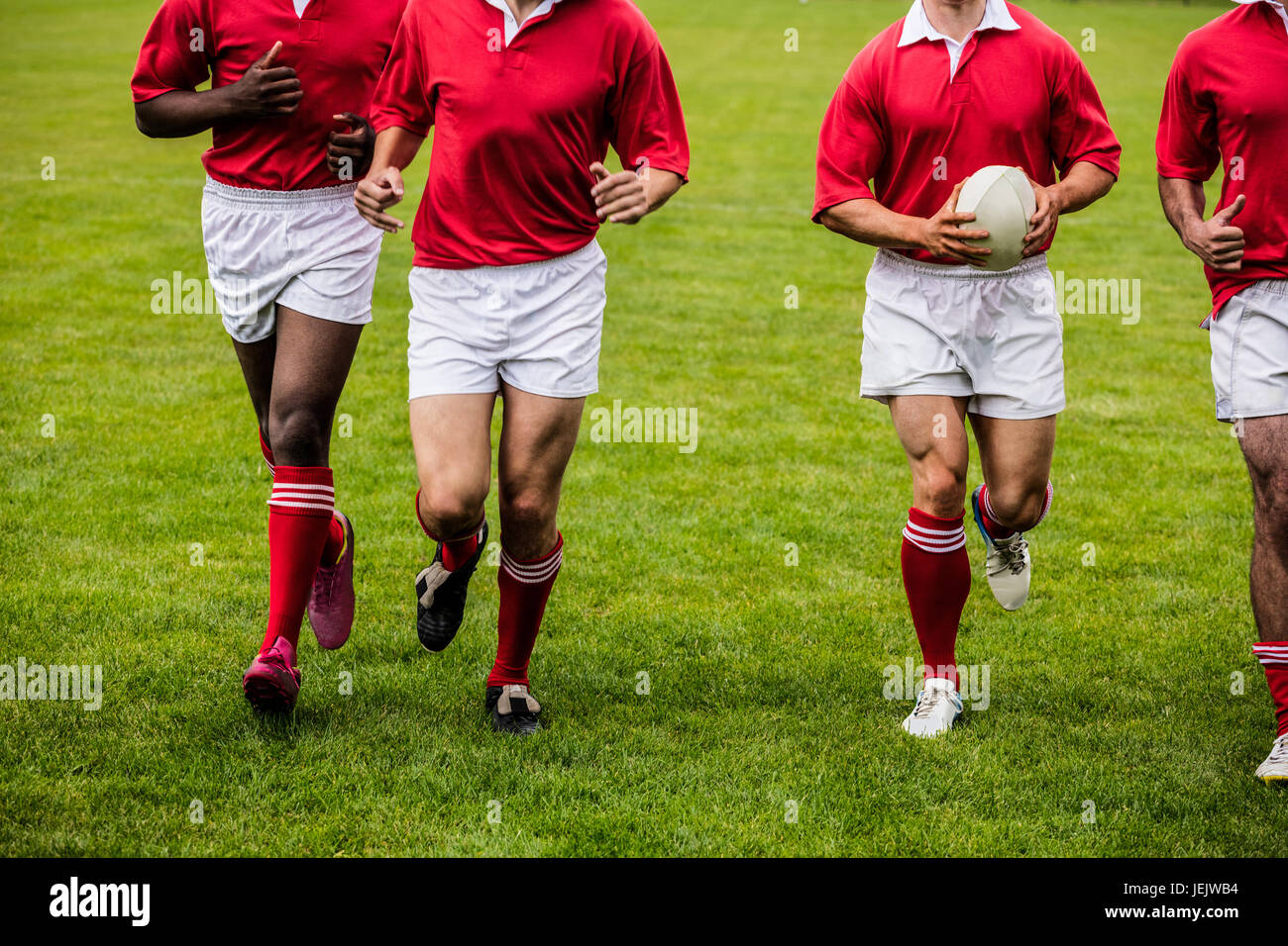 Rugby players jogging with ball Stock Photo - Alamy