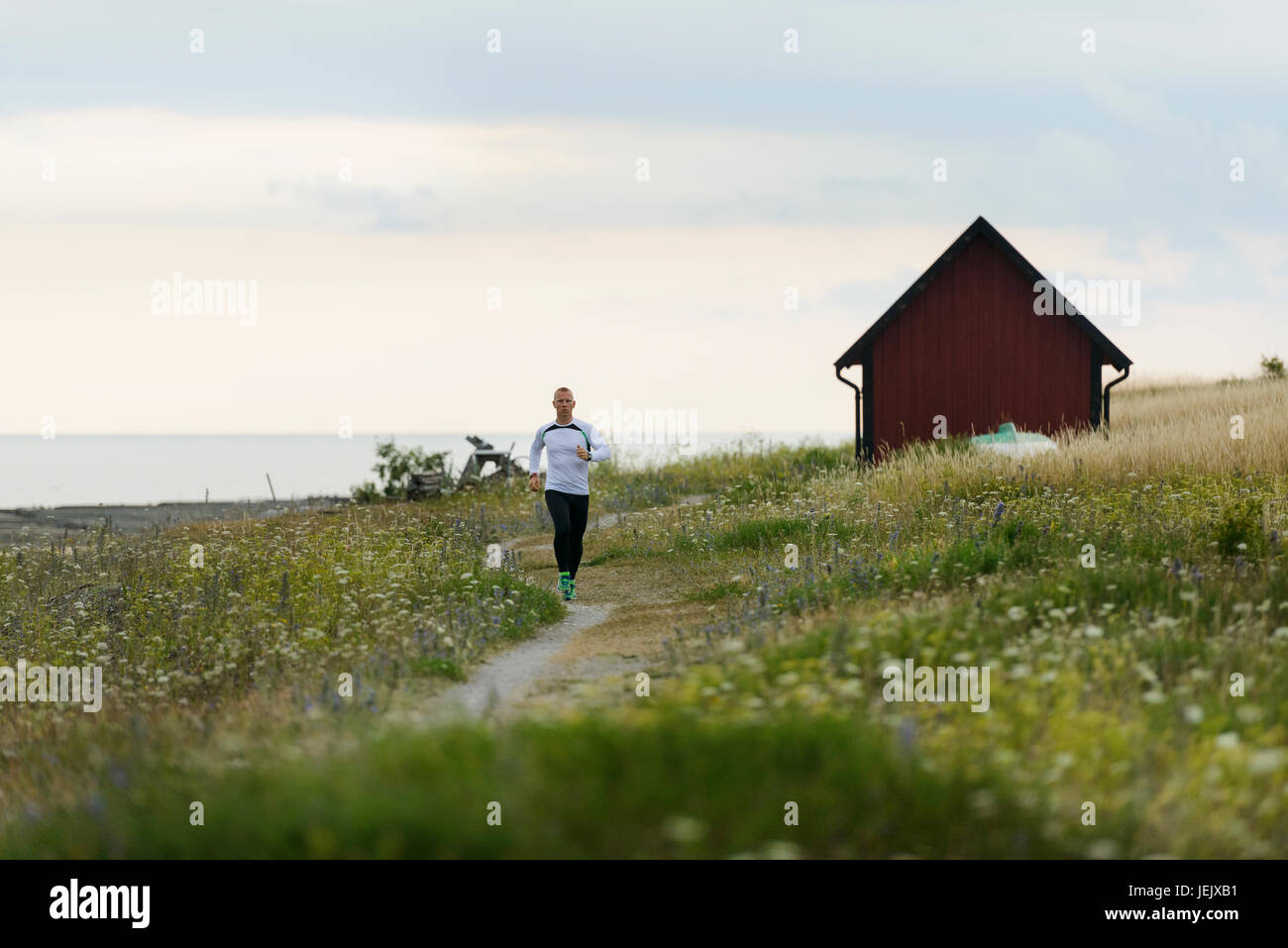 Young man running through meadow Stock Photo - Alamy