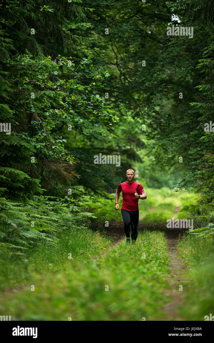 Young man running through forest Stock Photo - Alamy