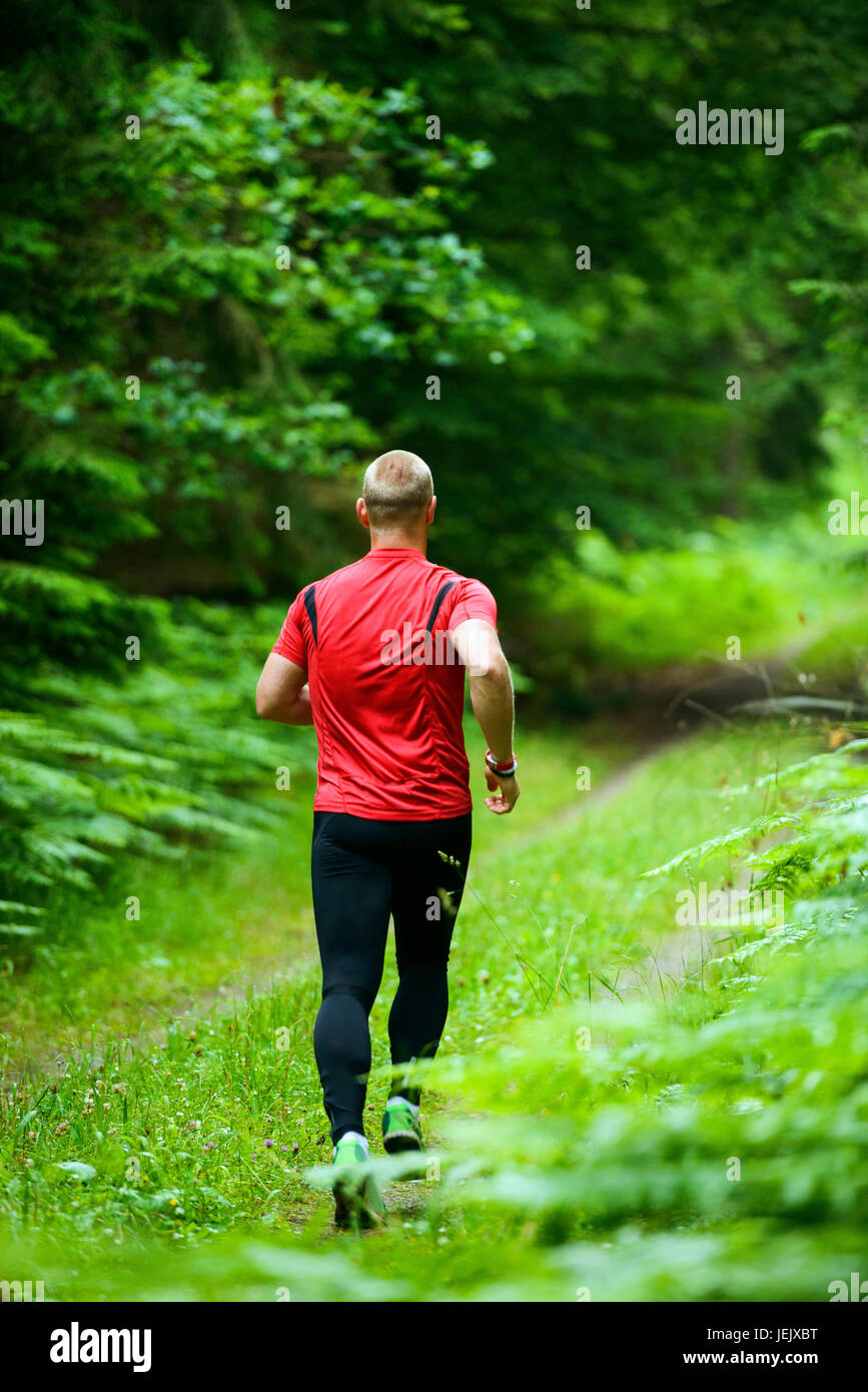 Young man running through forest Stock Photo - Alamy