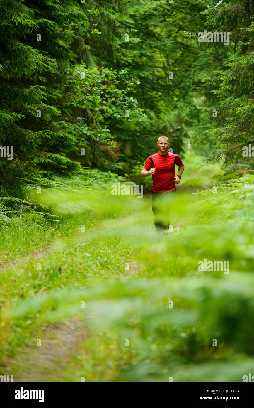 Young man running through forest Stock Photo - Alamy