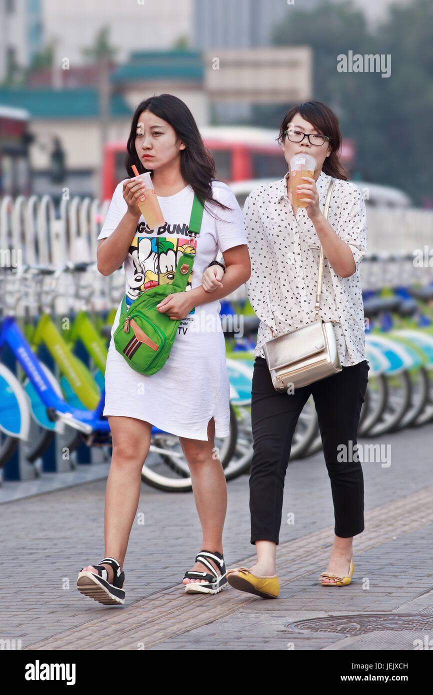 BEIJING-AUG. 5, 2015. Two girls enjoy soft drink during walk. National ...