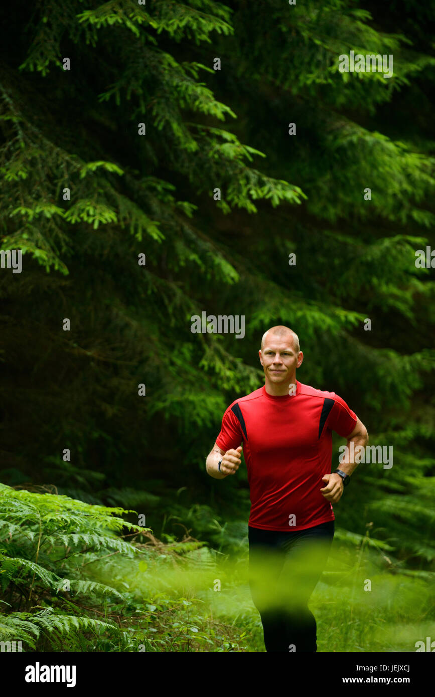 Young man running through forest Stock Photo - Alamy