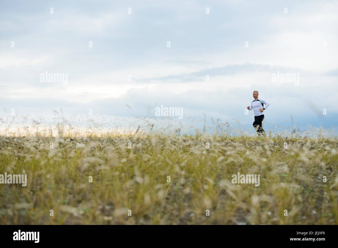 Young man running through meadow Stock Photo - Alamy