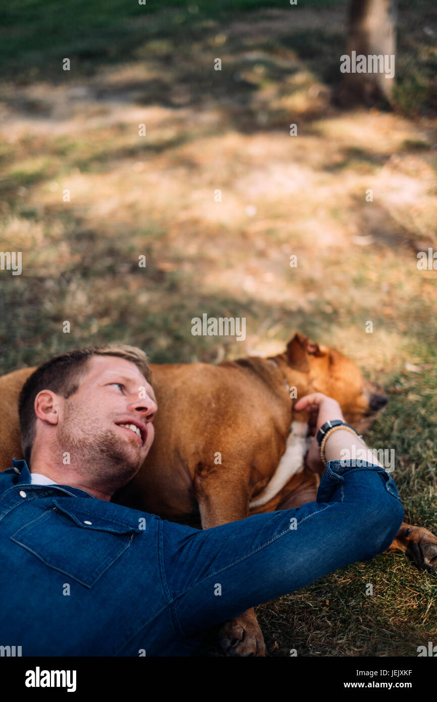 Young man lying down with his dog Stock Photo - Alamy