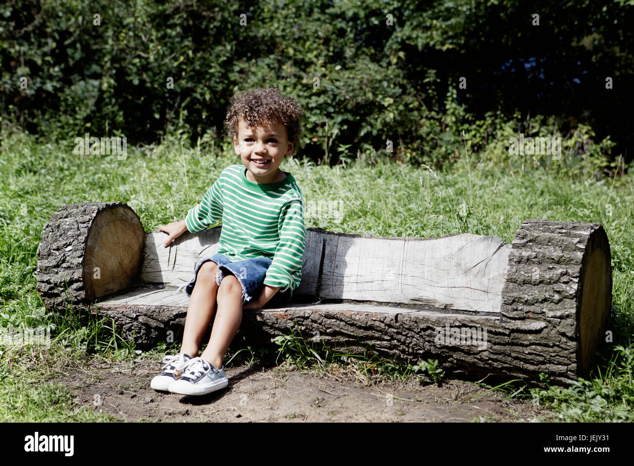 Boy on log bench Stock Photo - Alamy