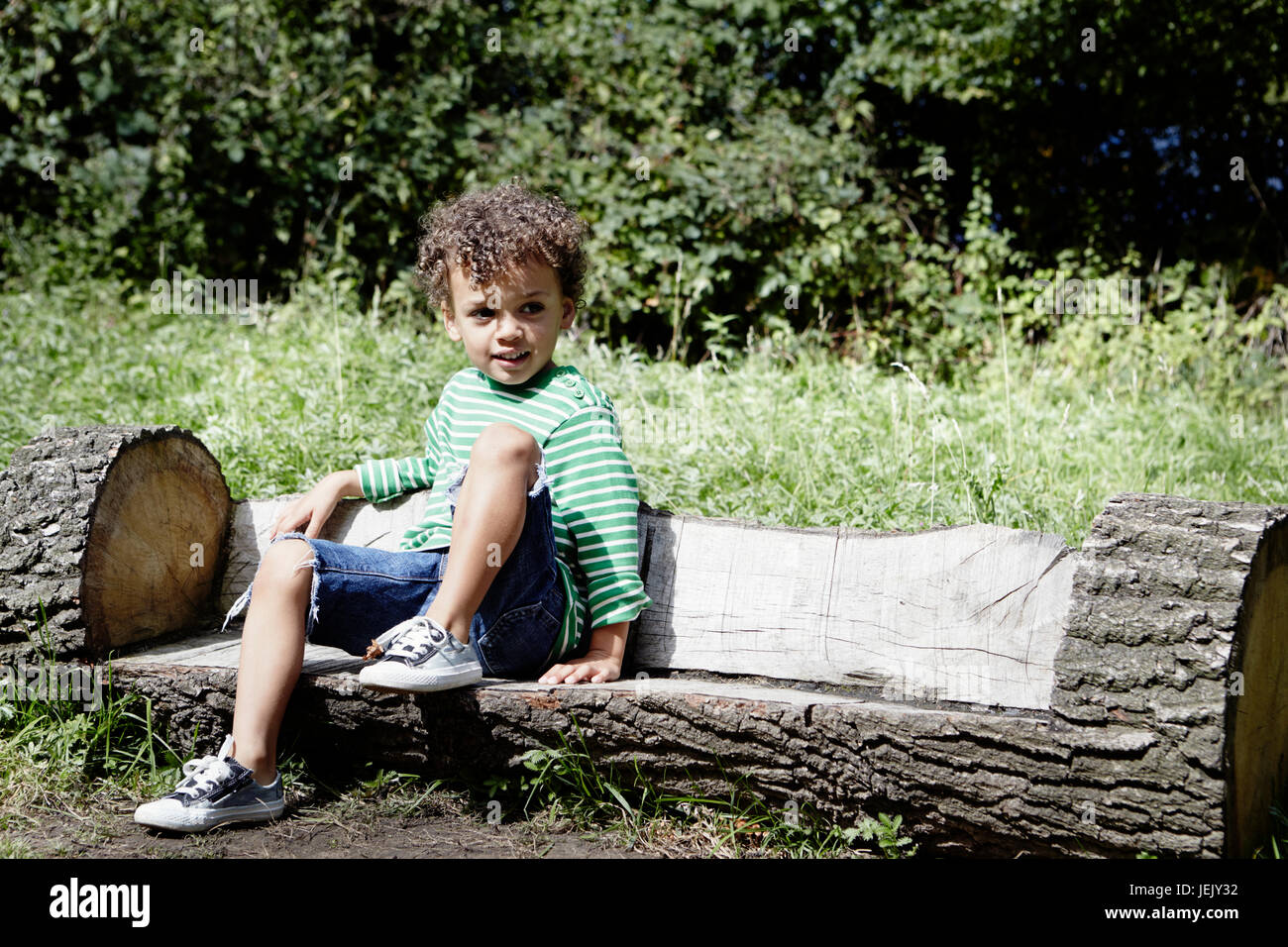 Boy on log bench Stock Photo - Alamy