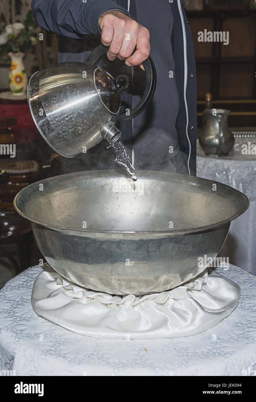 The priest assistant filled Christening Baptismal Font with Holy Water ...
