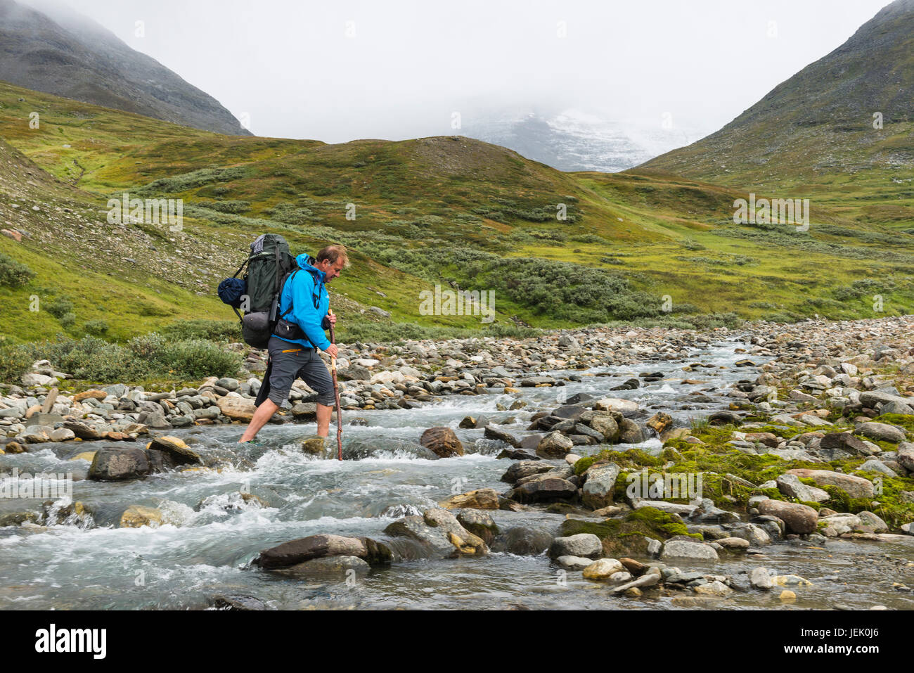 Man crossing mountain river Stock Photo - Alamy