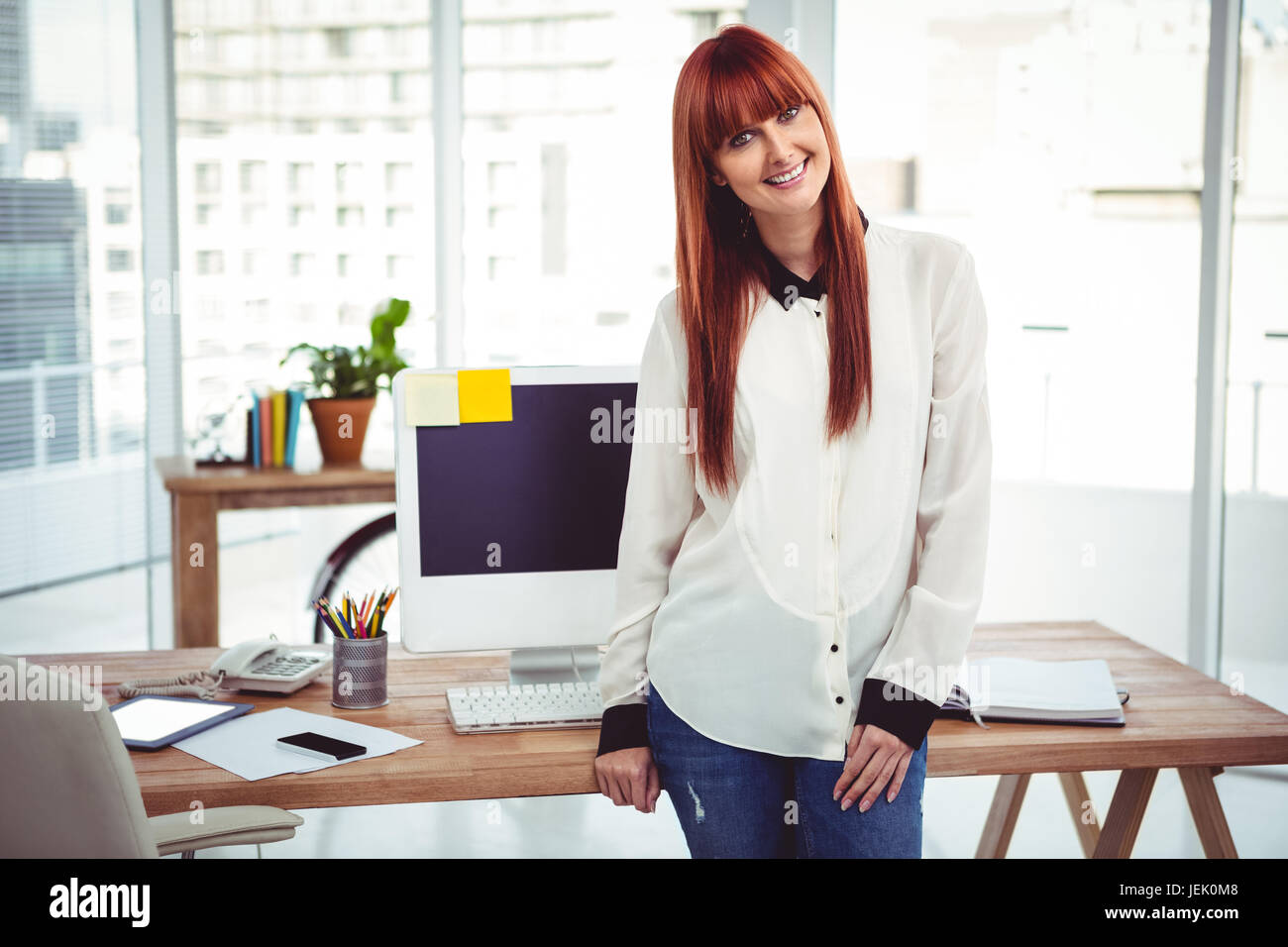 Smiling hipster businesswoman front of her desk Stock Photo - Alamy