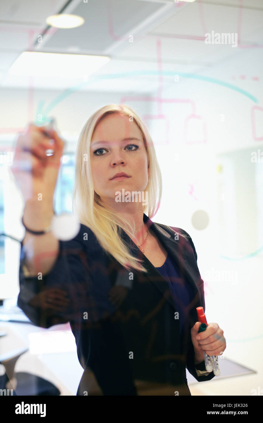 Businesswoman writing on transparent board hi-res stock photography and ...