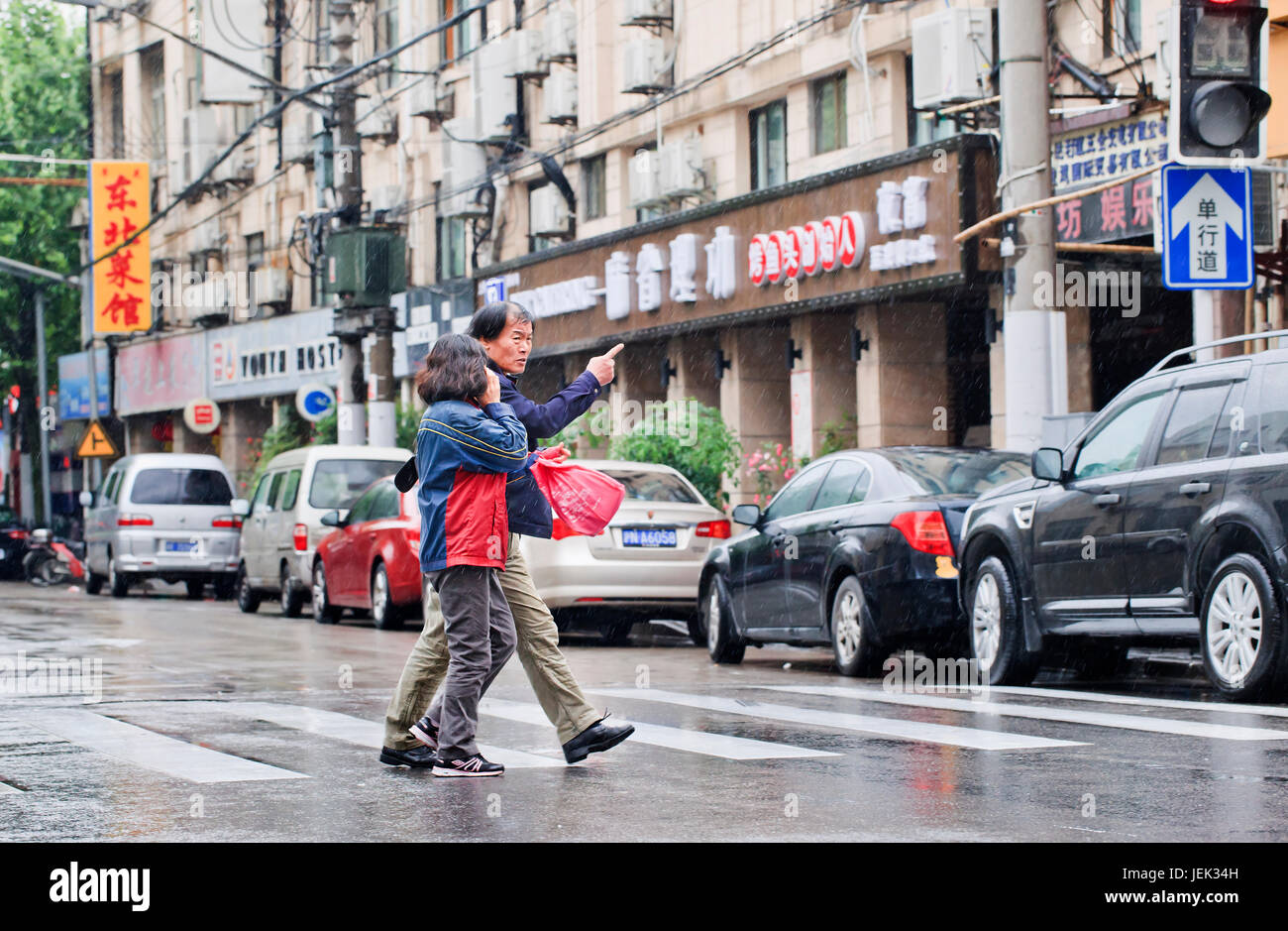 SHANGHAI–MAY 4, 2014. Pedestrians crossing street on rainy zebra path ...