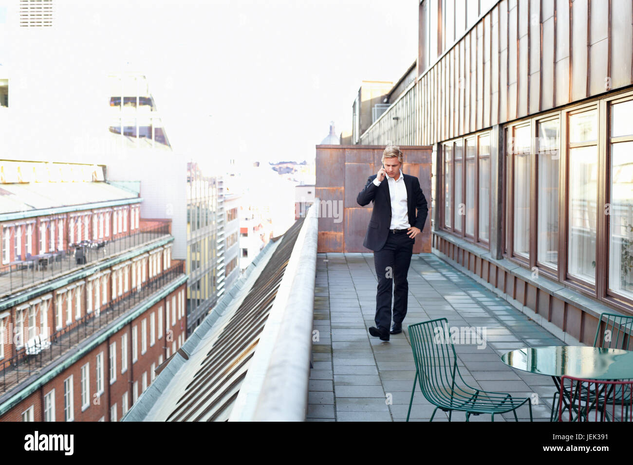 Businessman talking via cell phone on terrace Stock Photo - Alamy