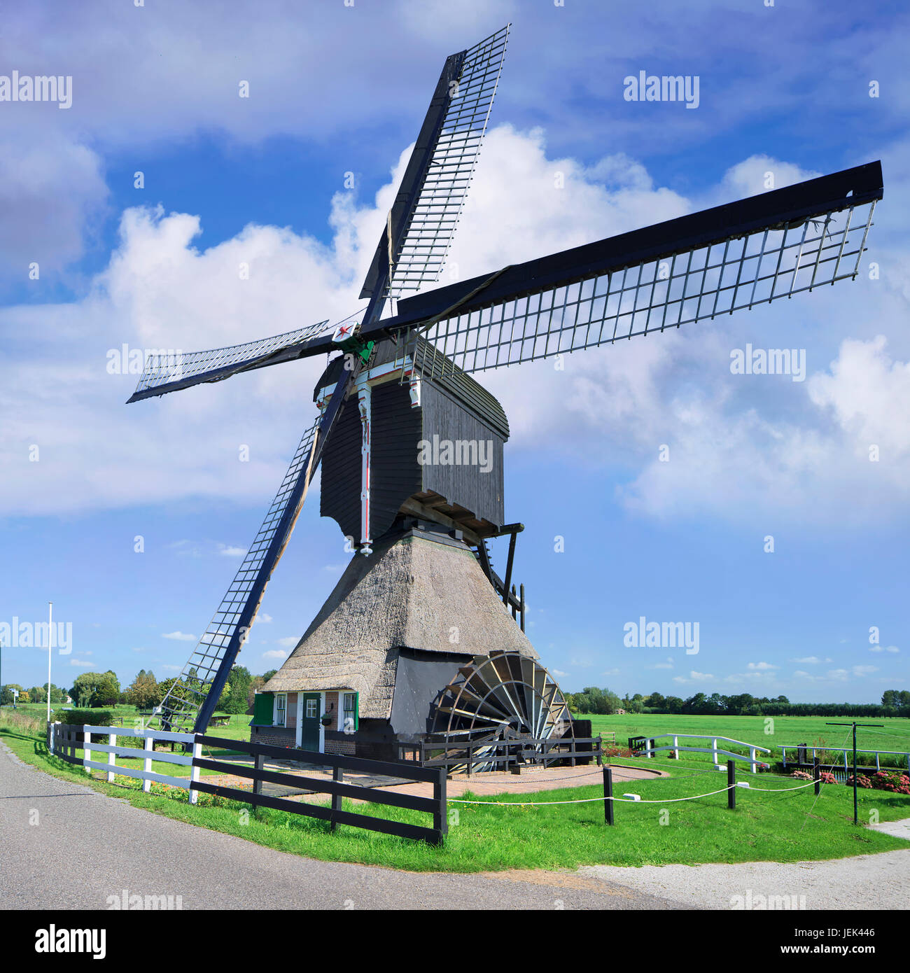 Ancient wooden drainage windmill with a water-wheel against blue sky ...