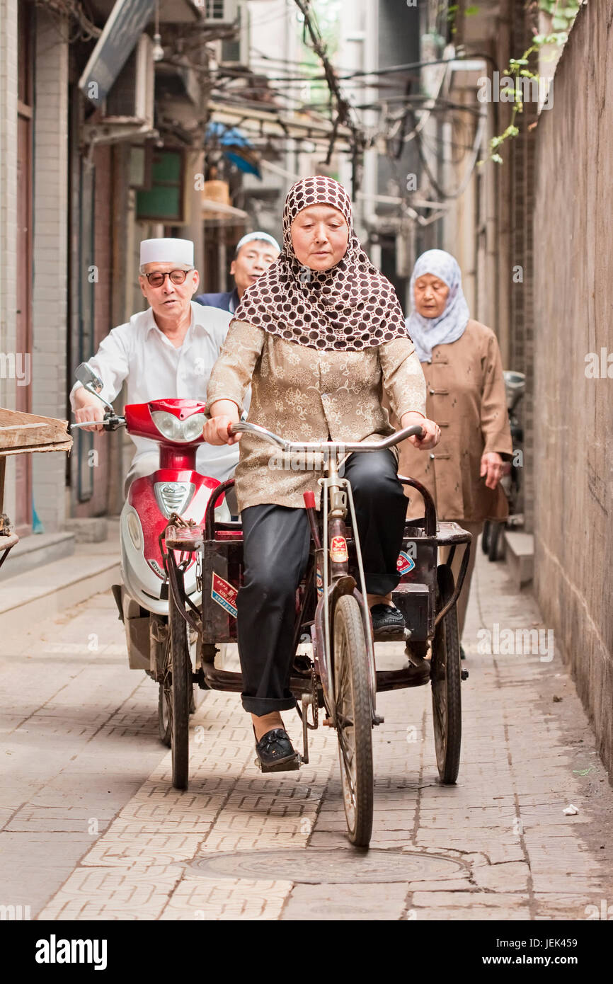 XI’AN, CHINA – MAY 22, 2009. Muslims cycles in an alley at Muslim ...