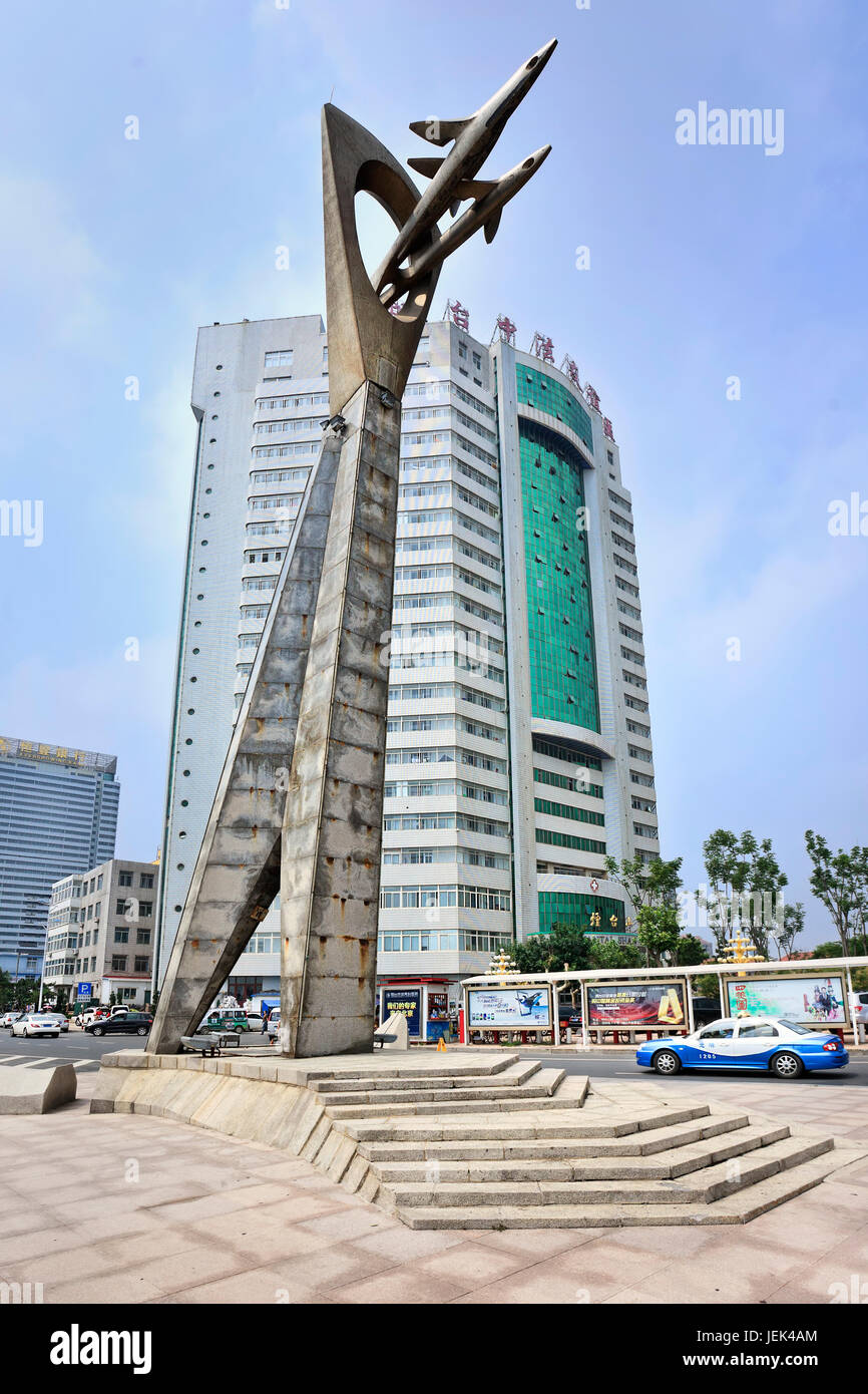 YANTAI-CHINA-JULY 17. Tall statue with building on background. Small ...