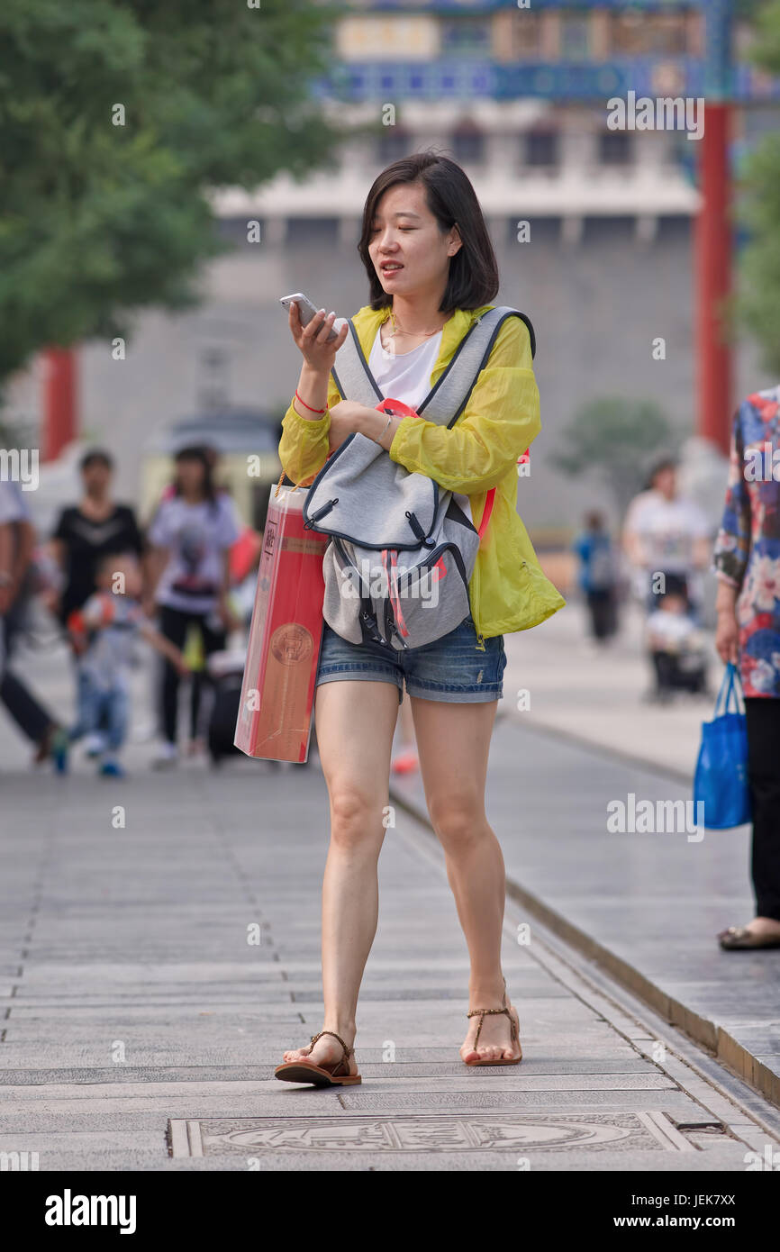 BEIJING-JUNE 9, 2015. Fashionable young Chinese girl busy with her ...