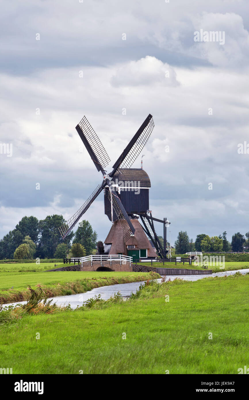 Ancient wooden windmill near small canal, Kinderdijk, The Netherlands ...