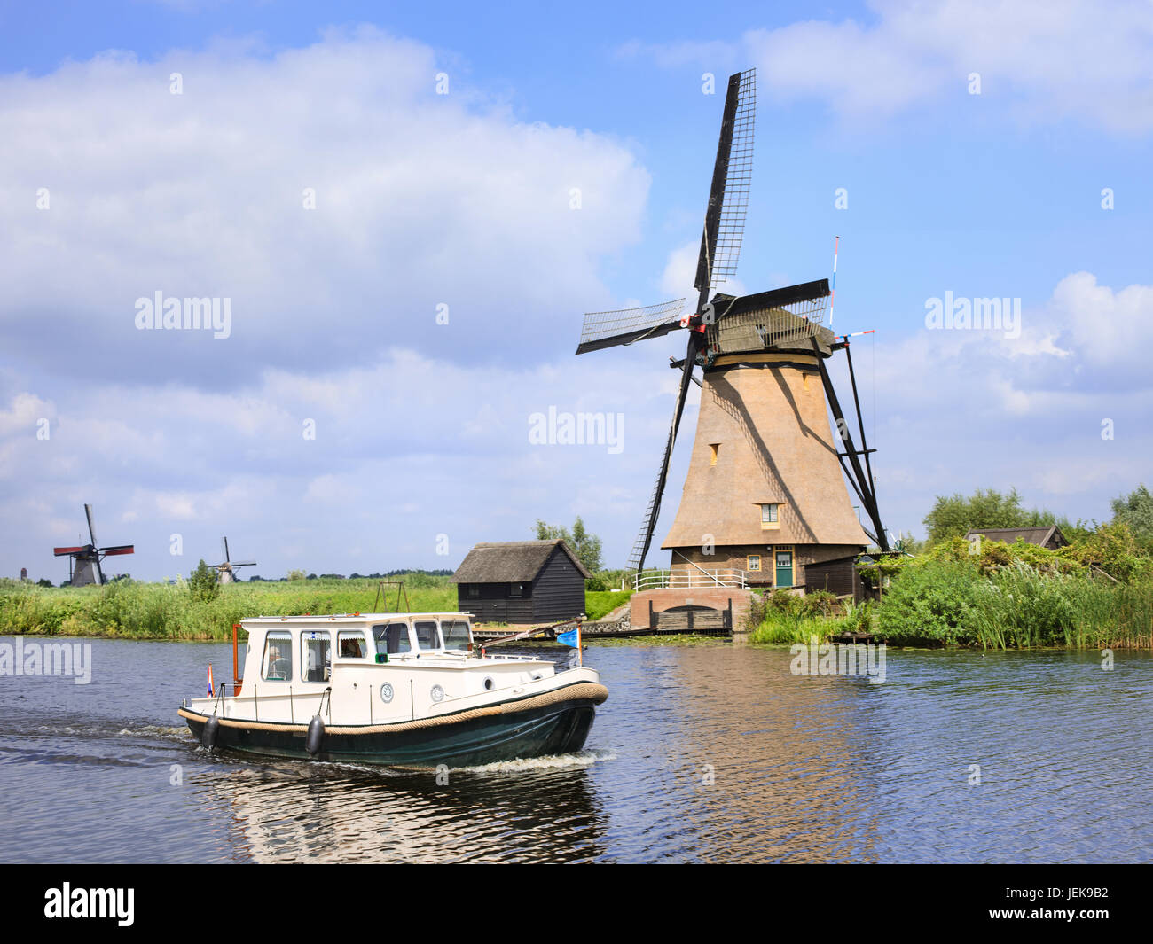 Sunny scenery with a small boat and ancient windmill, Kinderdijk ...