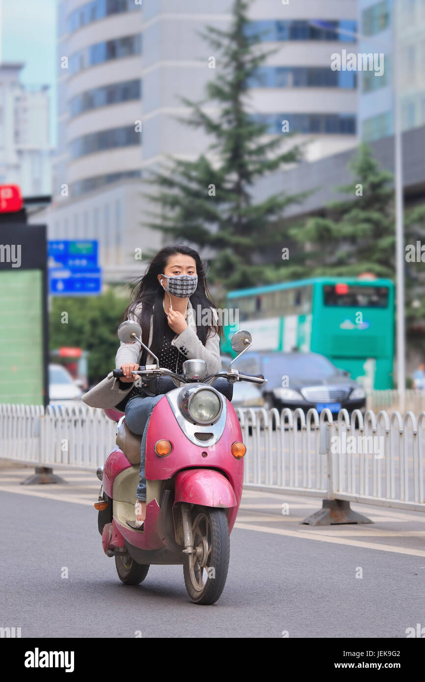 KUNMING-JUNE 30, 2014. Girl on retro design e-bike. Many electric bikes ...