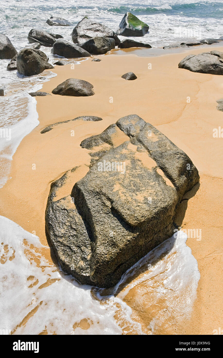 Massive rock, partially covered with sand on the beach in Sanya Island ...