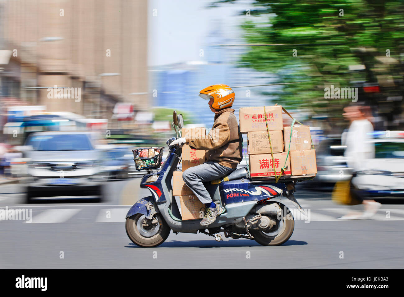 Man transports boxes on scooter. Many riders on engine scooters drive ...