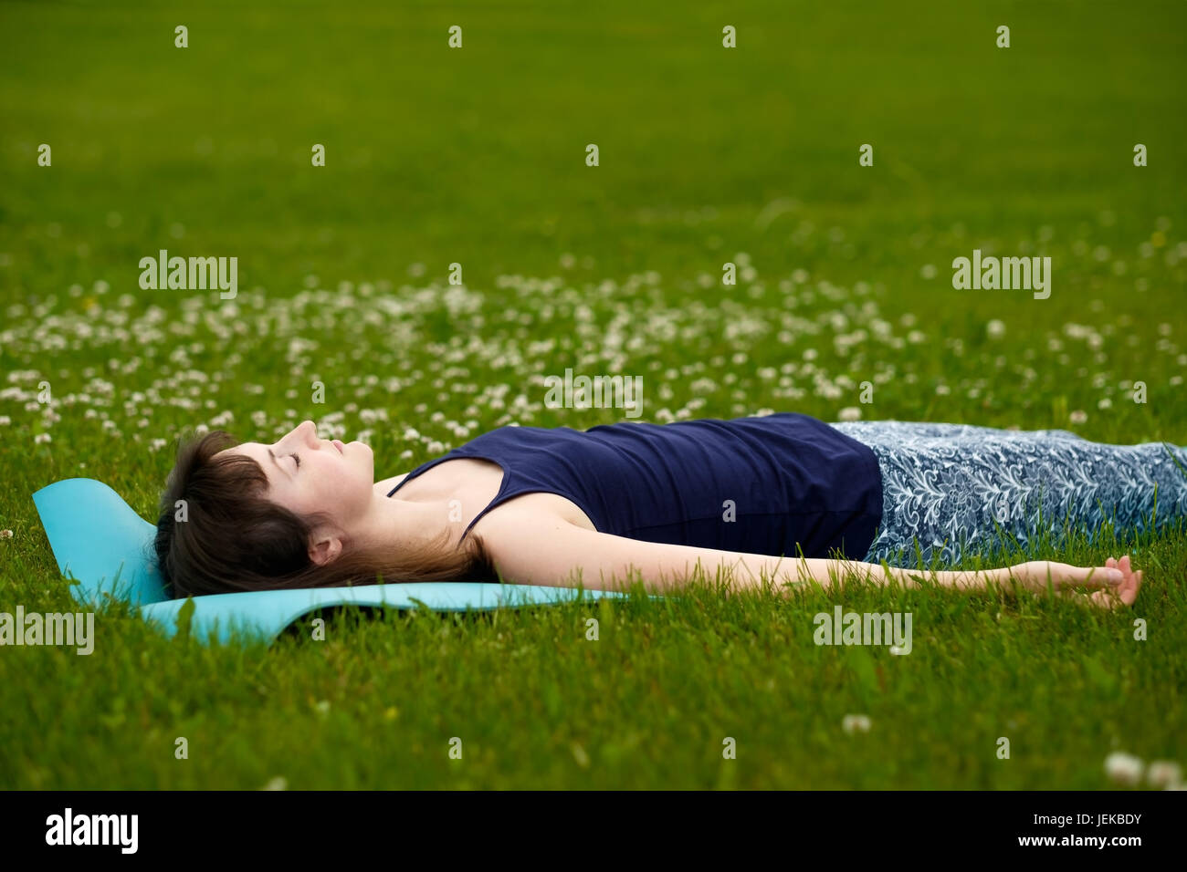 Girl doing yoga, meditating, Shavasana or corpse position in park on ...