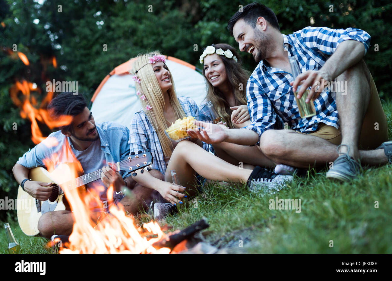 Cheerful young friends having fun by campfire in nature Stock Photo - Alamy