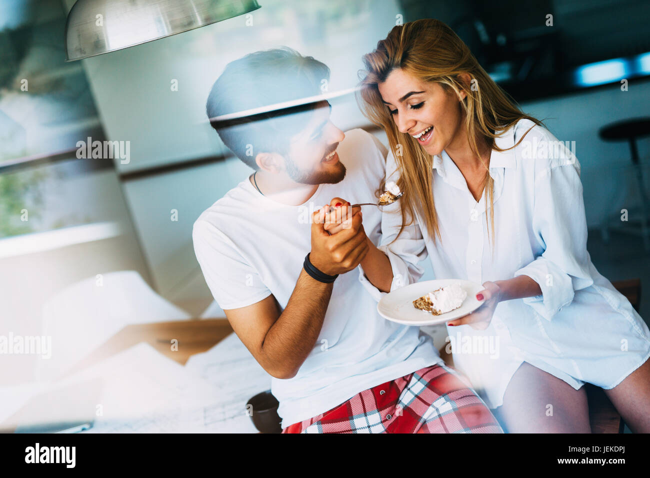 Cute young cheerful couple spending time at home eating cake Stock ...