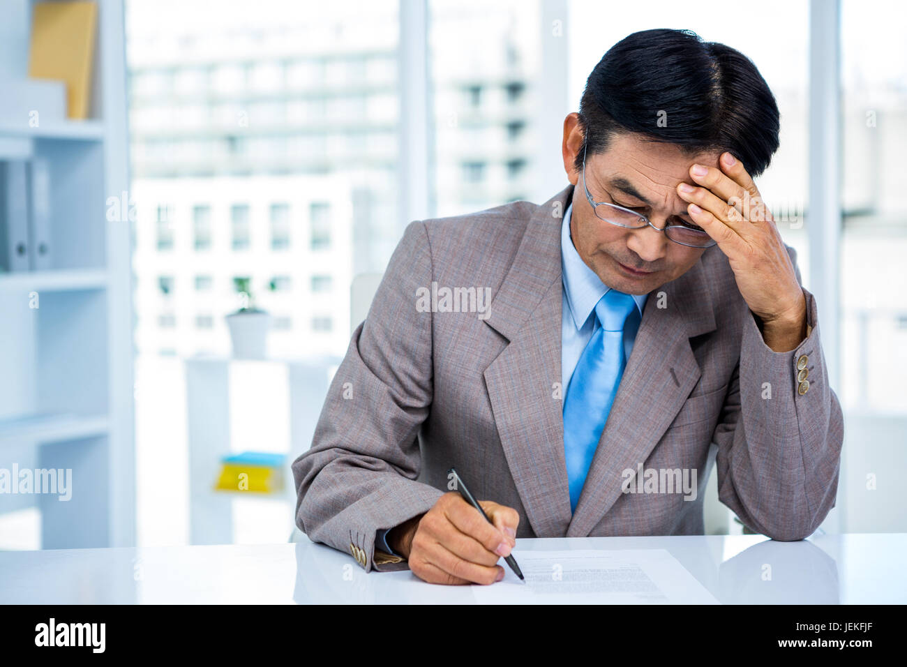 Worried asian businessman on his desk Stock Photo - Alamy