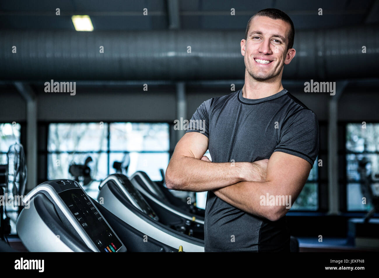 Muscular man on treadmill with crossed arms Stock Photo - Alamy
