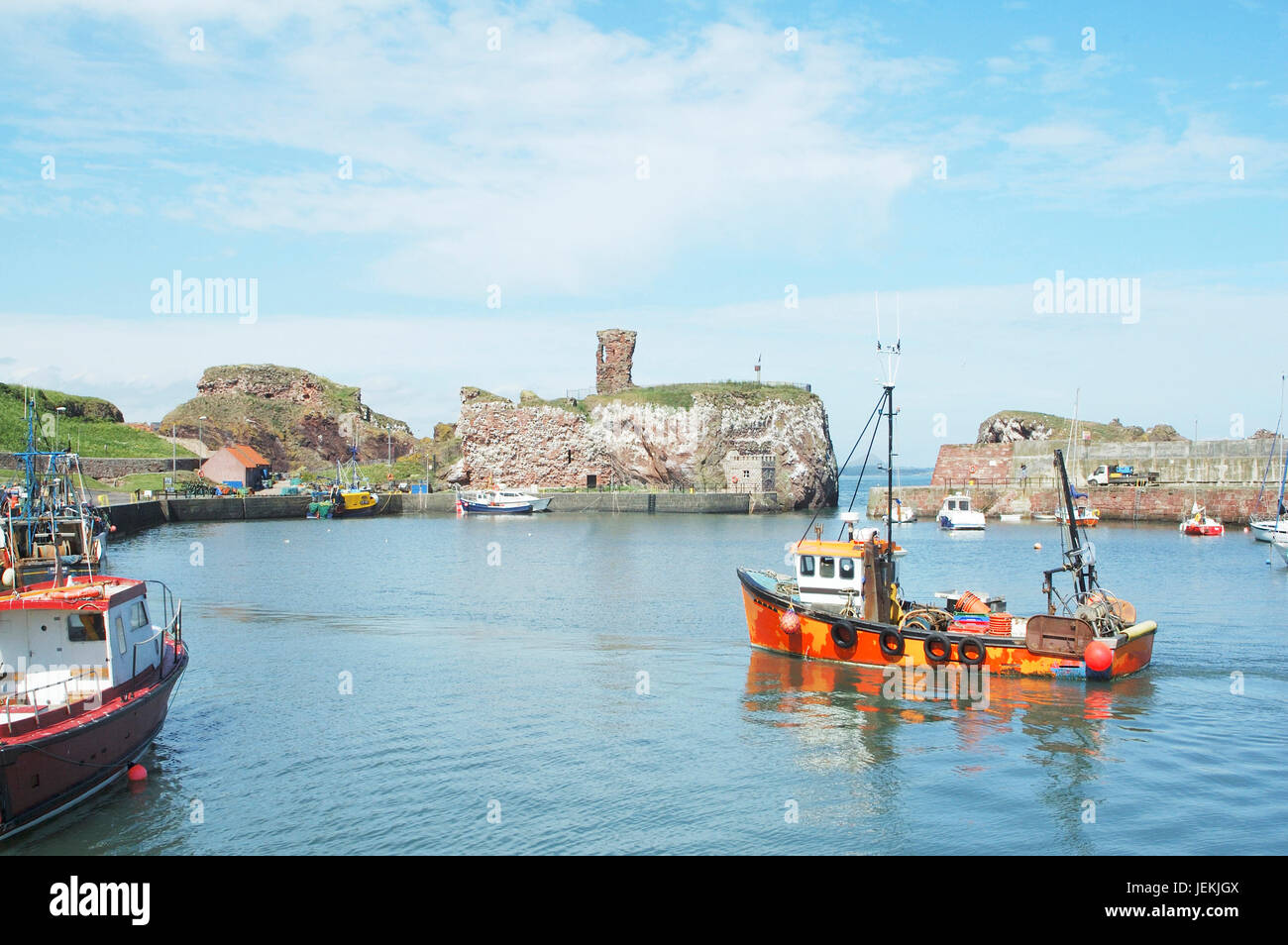 Dunbar castle ruins at entrance to Dunbar harbour with fishing boats ...