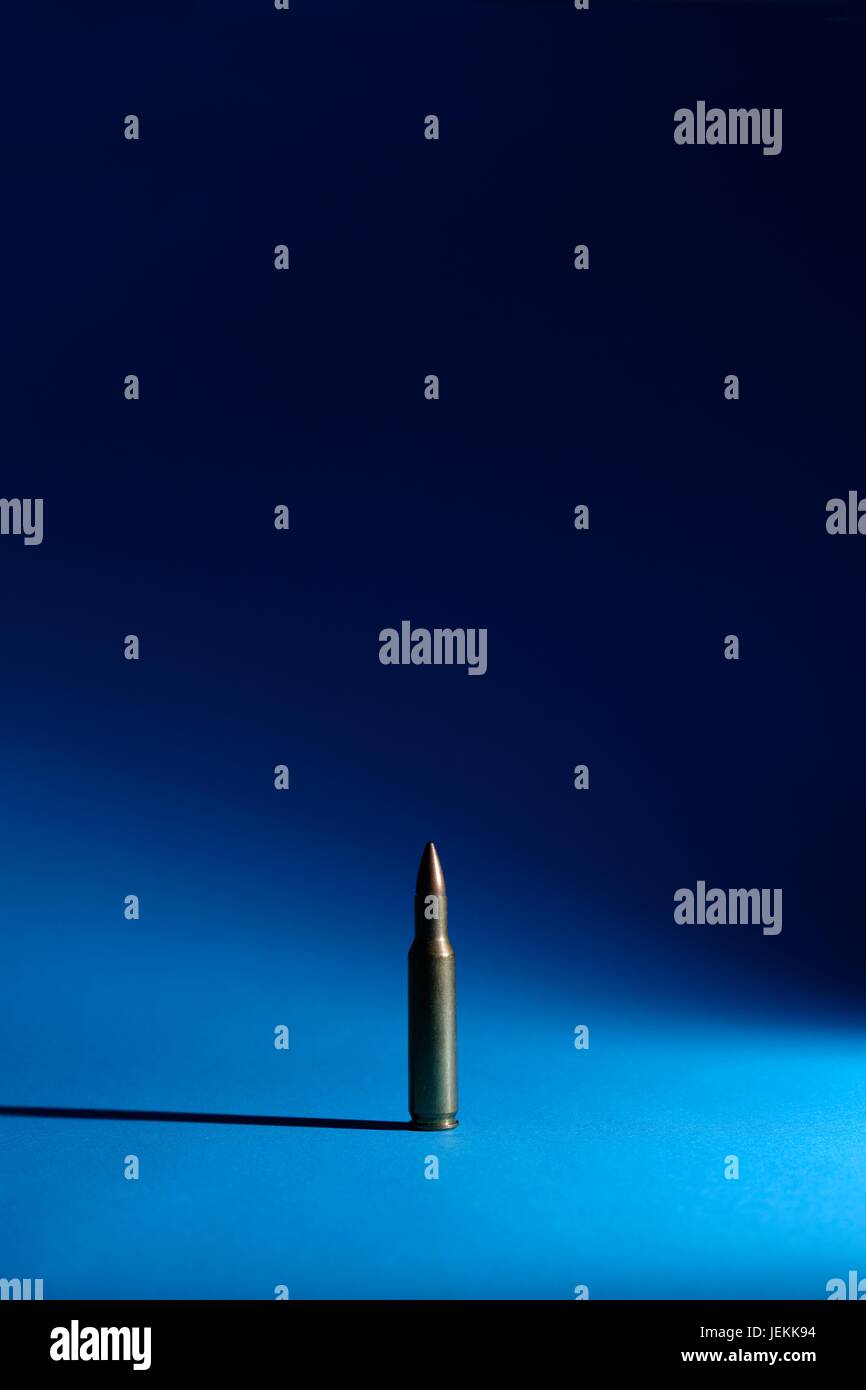 A single bullet is standing on a blue ground Stock Photo - Alamy