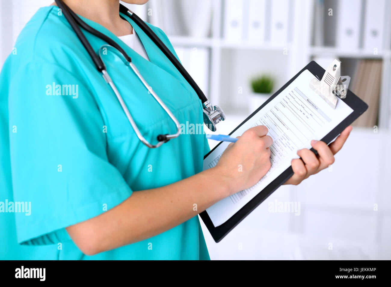 Close-up of a female doctor is filling out application form or medical ...
