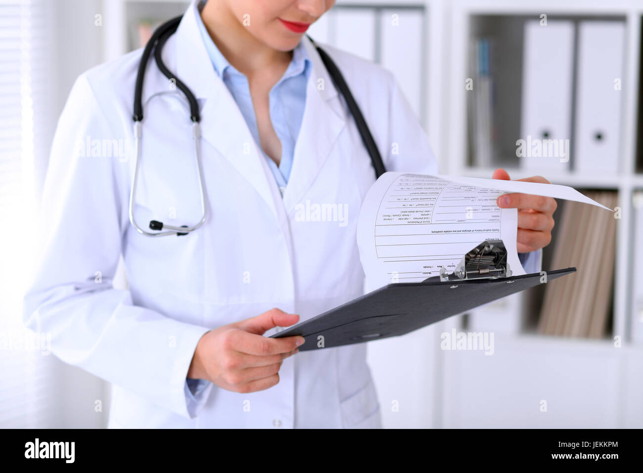 Close-up of a female doctor is filling out application form or medical ...