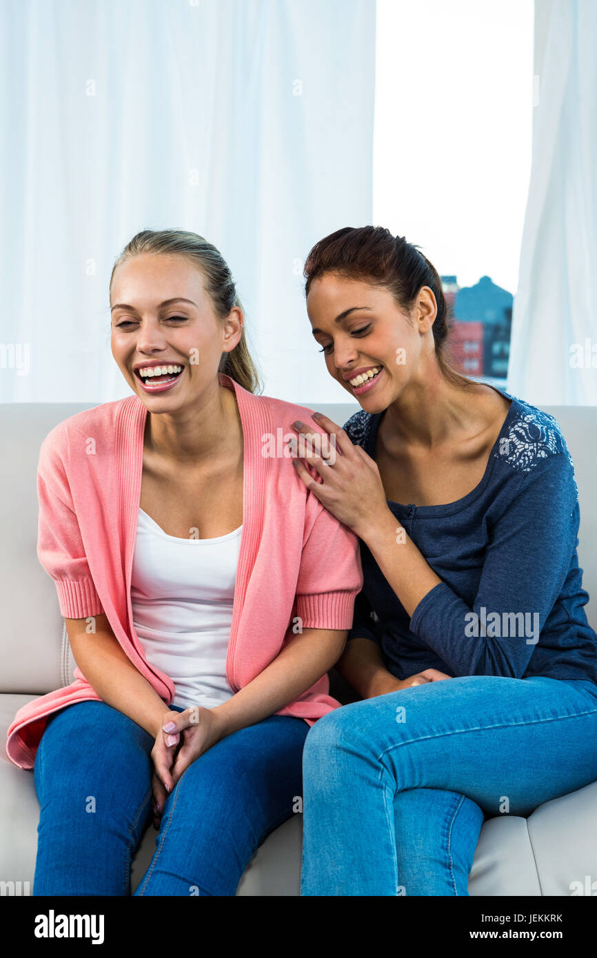 Happy friends laughing on sofa Stock Photo - Alamy