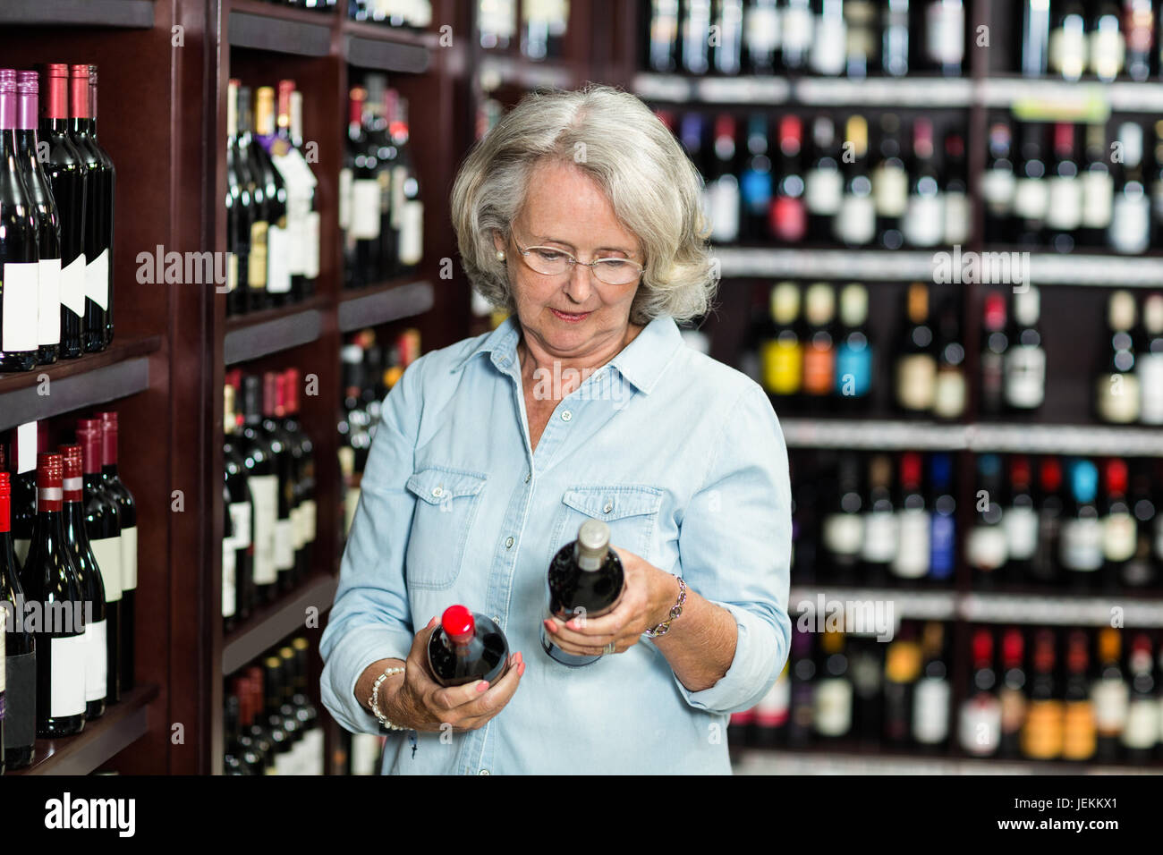 Smiling senior woman choosing wine Stock Photo - Alamy