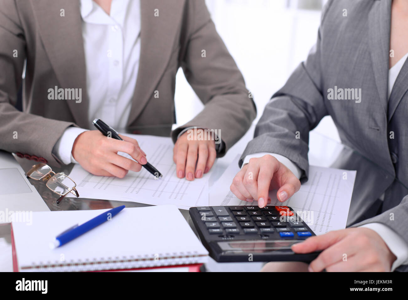 Two female accountants counting on calculator income for tax form ...