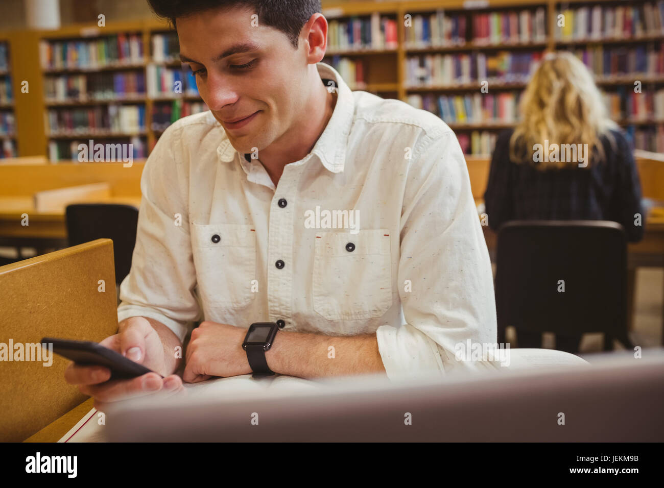Smiling student using his smartphone Stock Photo - Alamy