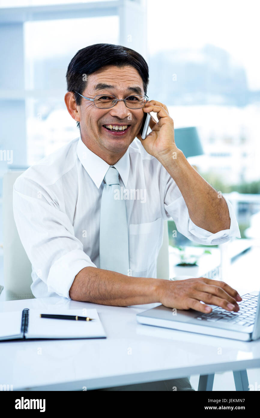 Smiling asian businessman calling someone Stock Photo - Alamy