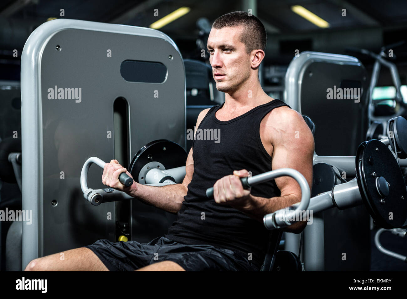 Serious muscular man using exercise machine Stock Photo - Alamy