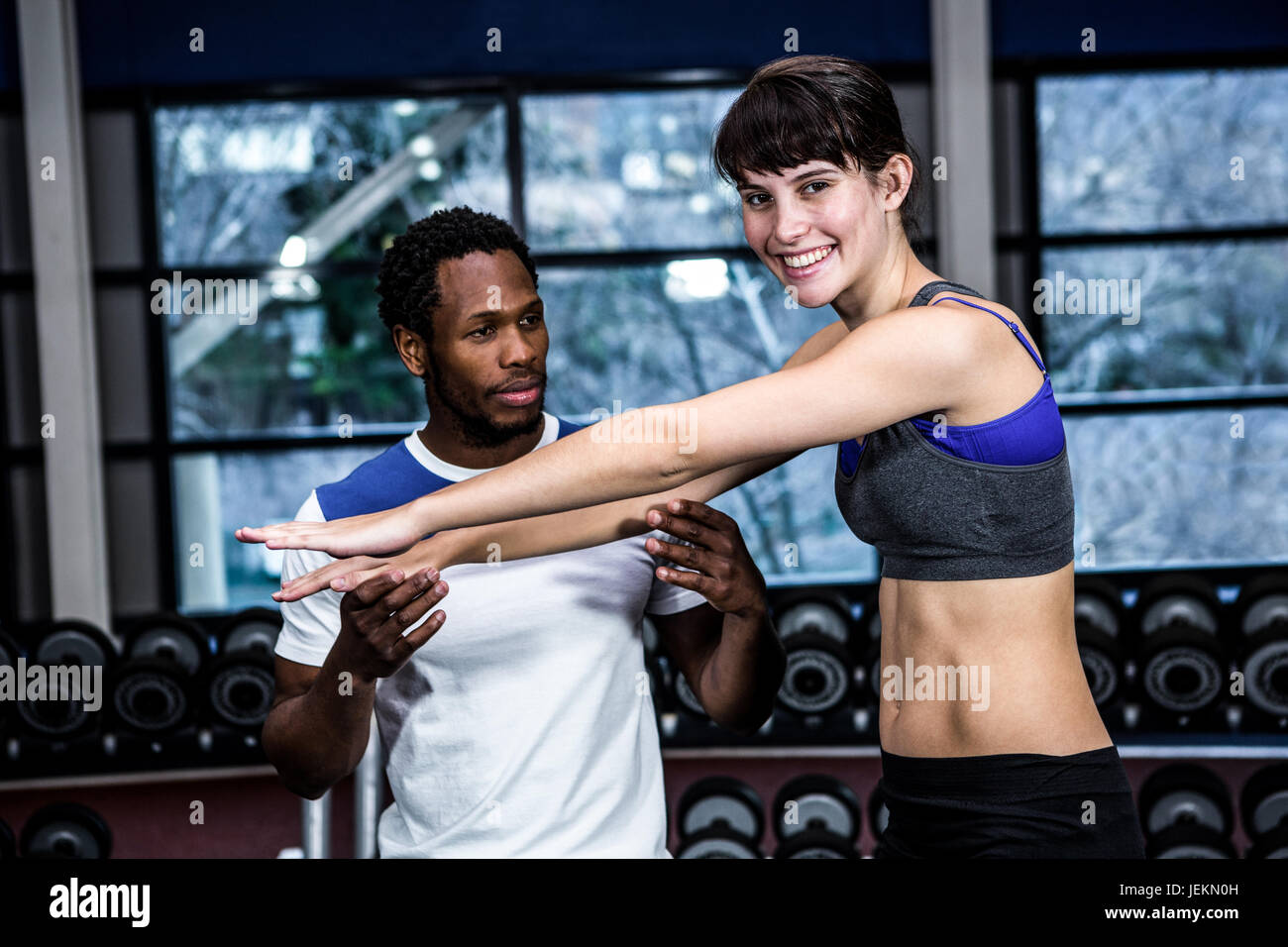 Male trainer assisting fit woman Stock Photo - Alamy