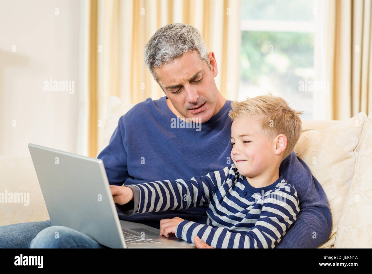 Father and son using laptop on the sofa Stock Photo - Alamy