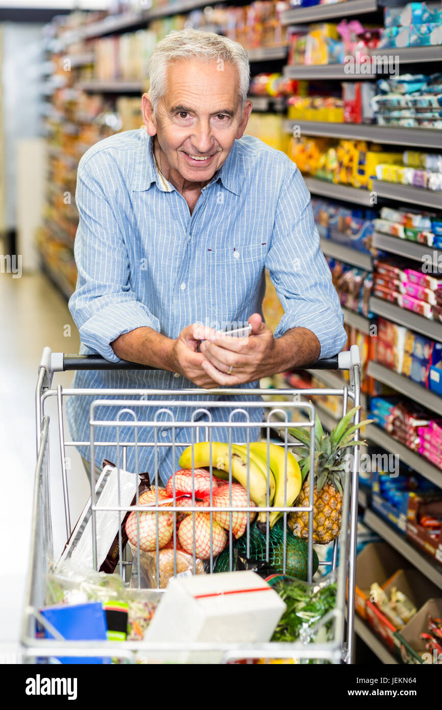 Senior man using phone at grocery store Stock Photo - Alamy