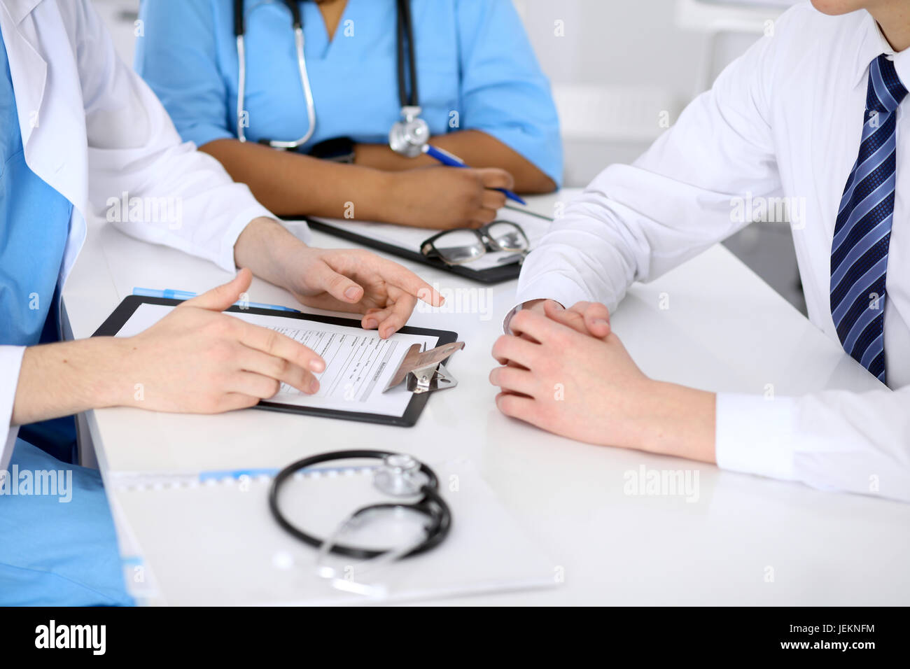 Two doctors and male patient discussing medical history at the table ...