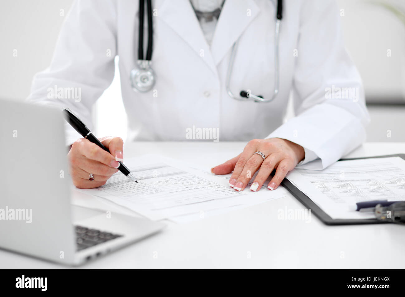 Close-up of a female doctor filling out application form , sitting at ...
